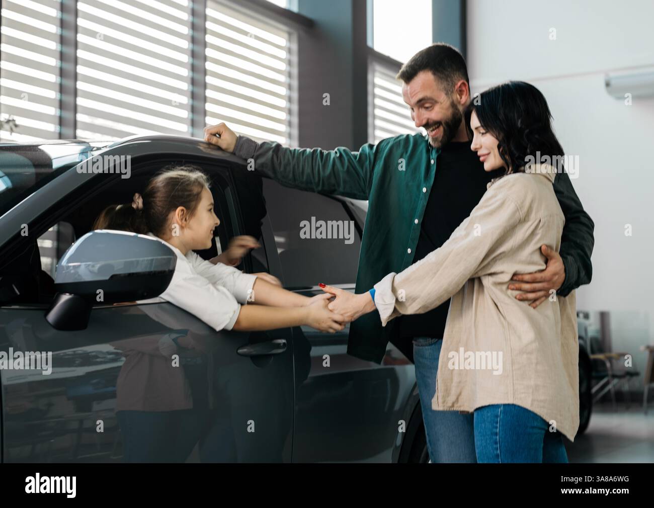 A happy young family in a modern car dealership after completing the ...