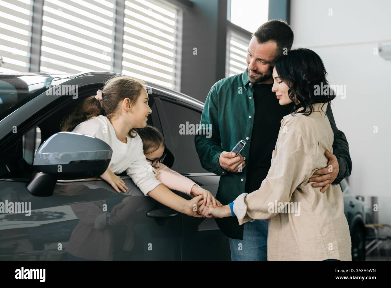 A happy young family in a modern car dealership after completing the ...