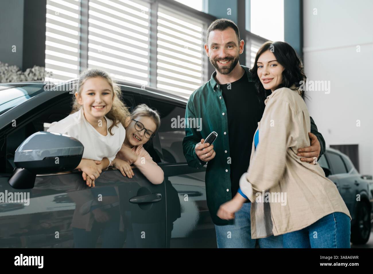A happy young family in a modern car dealership after completing the ...
