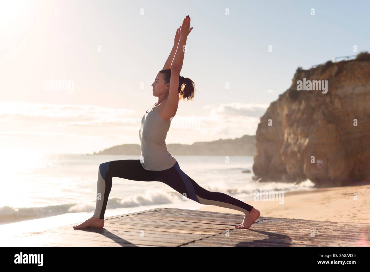 sporty woman practicing yoga at the beach, high crescent lunge Stock ...