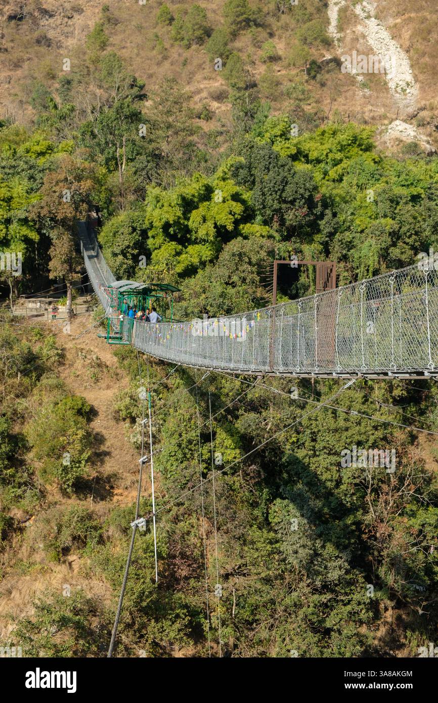 People gather at the entrance of a long suspension footbridge ...