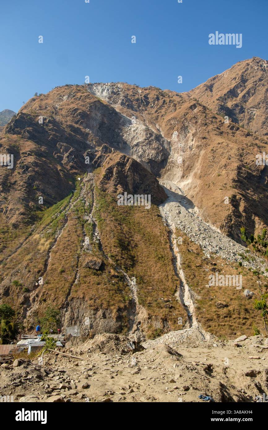 A massive landslide scars a steep, arid mountainside, evidence of ...