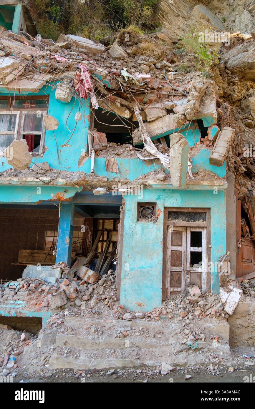 A bright blue building lies in ruins, crushed by rocks and debris from ...