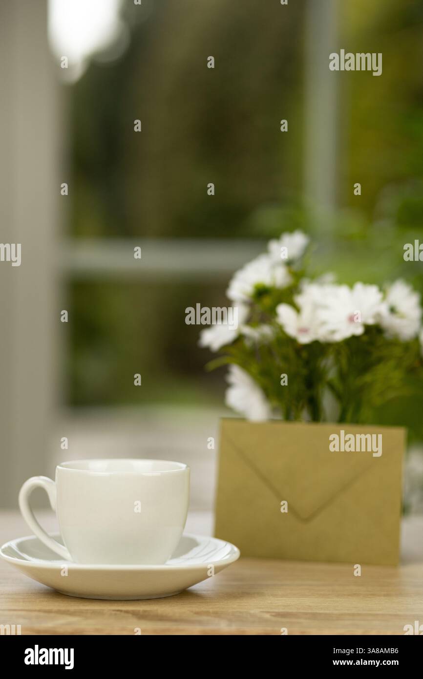 A cup of coffee, flowers and an envelope. Office desk with a cup of ...