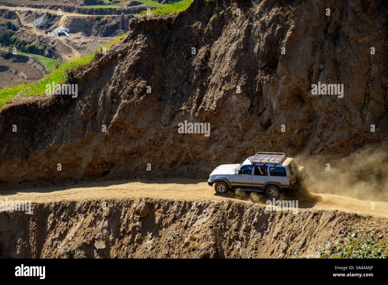 A silver SUV speeds along a perilous dirt track carved into a ...