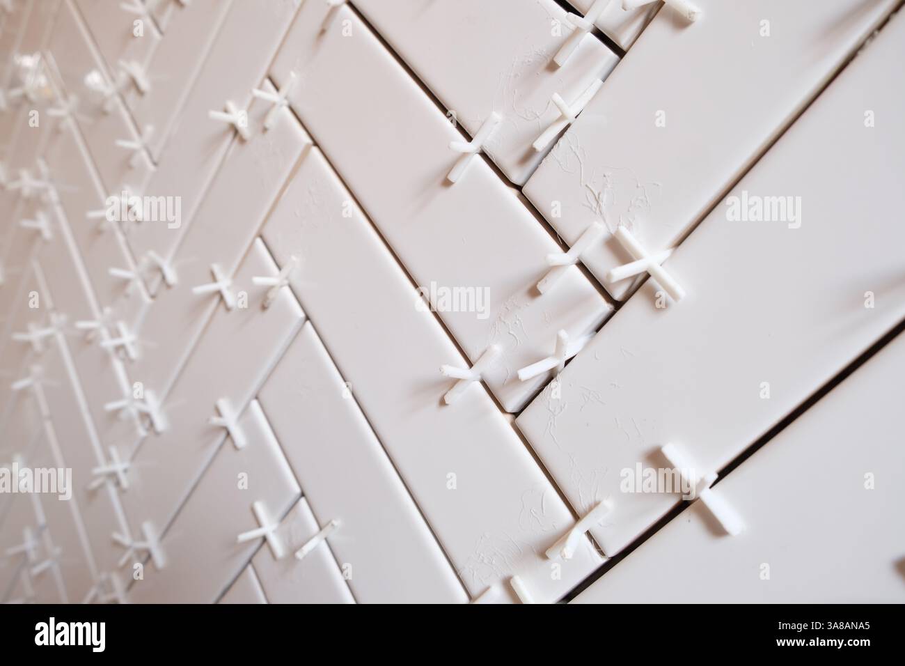 White subway tiles are installed in a herringbone pattern. Plastic ...