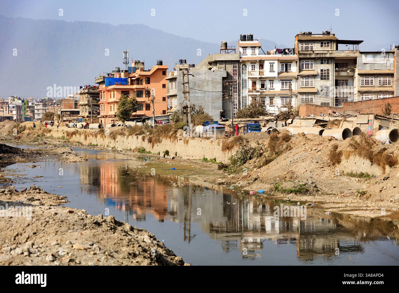 Urban scene in Kathmandu: Residents walk by a polluted river channel ...