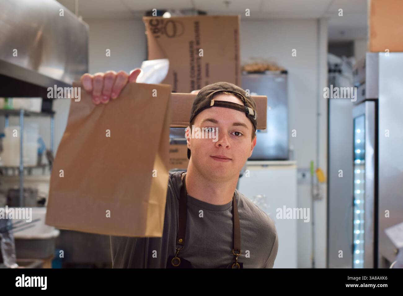Restaurant kitchen employee holding paper bag take out food order Stock ...