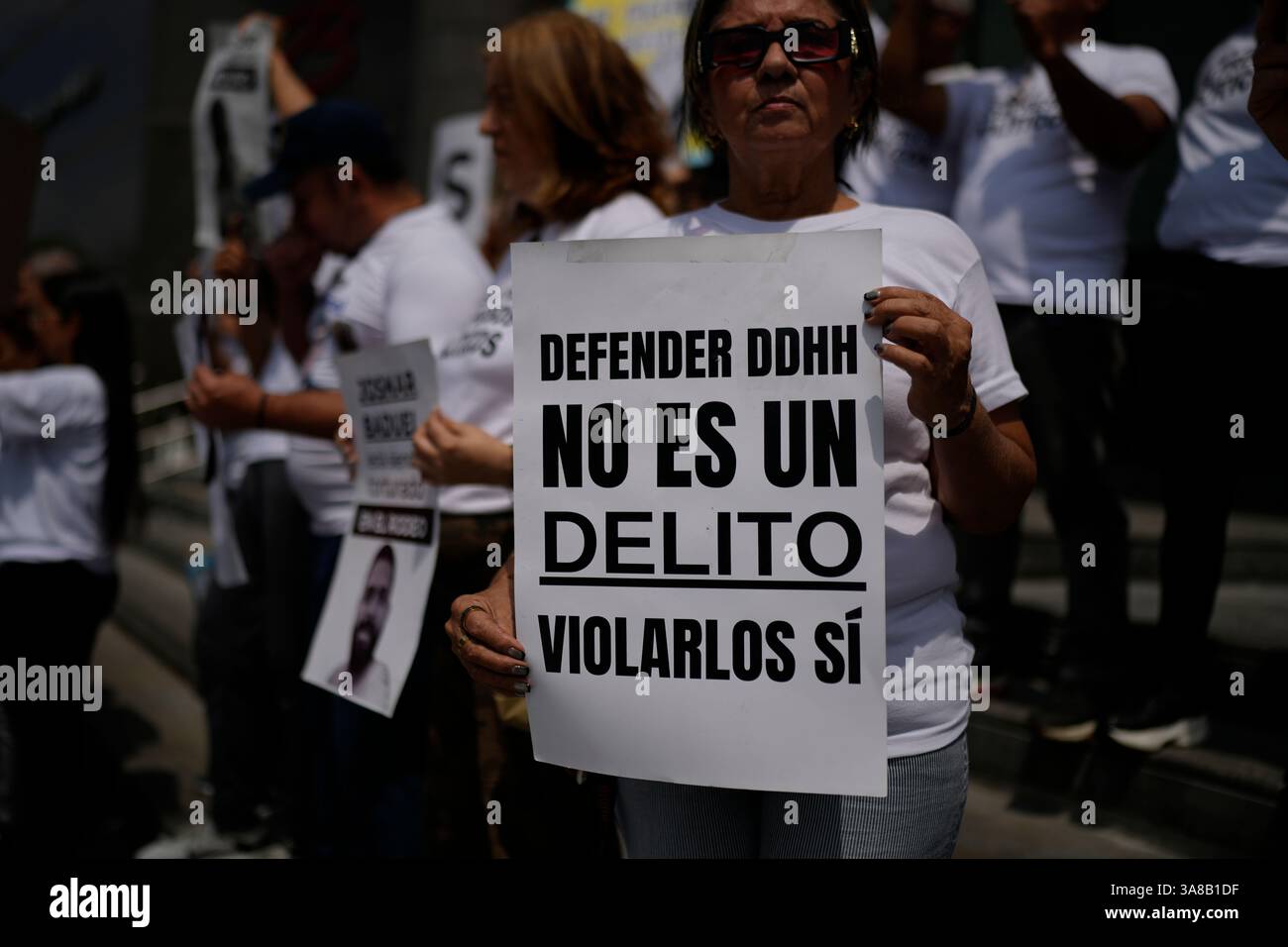A protester holds a sign that reads in Spanish "Defend human rights is ...