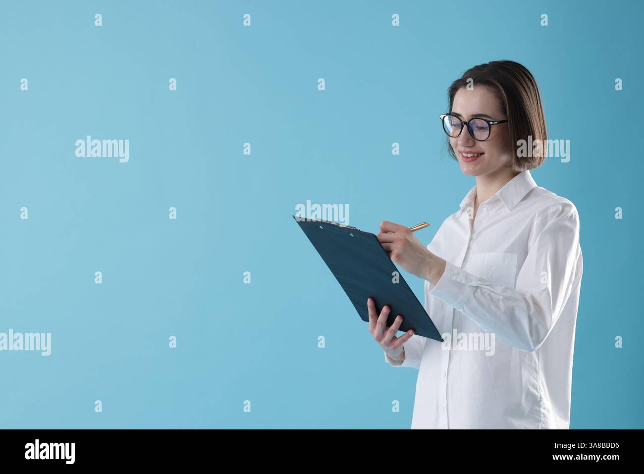 Young secretary with clipboard taking notes on light blue background ...