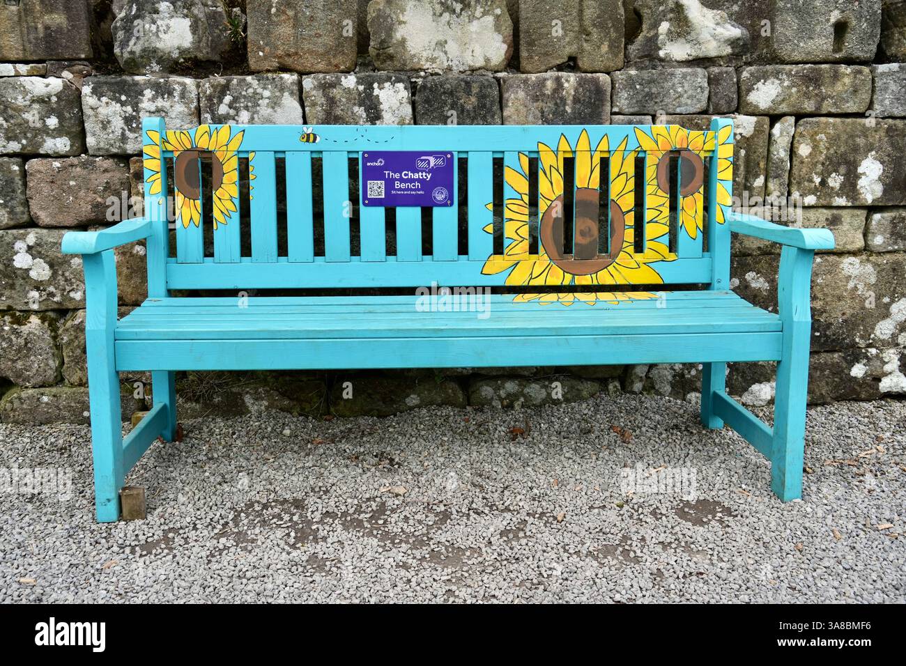 The Chatty Bench, a colourful wooden seat with stone wall behind Stock ...