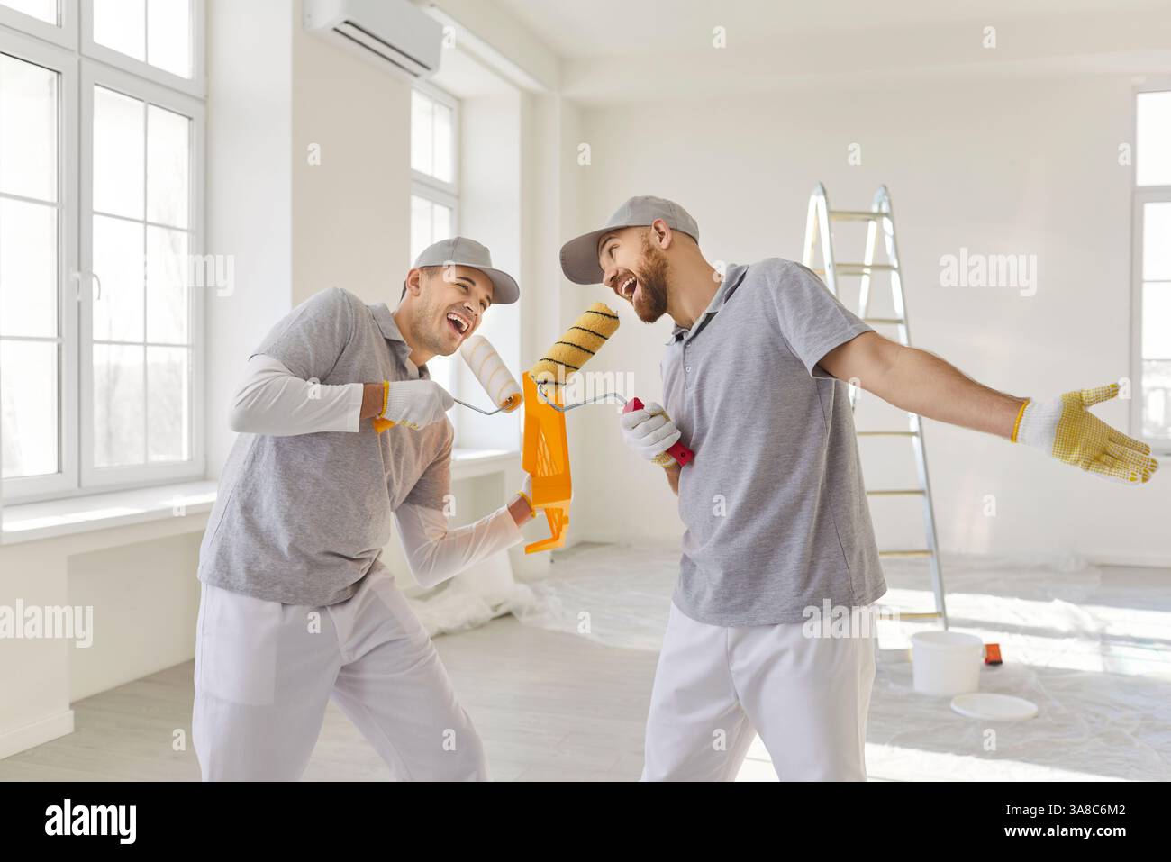 Two cheerful painters foolishing around while having fun, holding paint ...