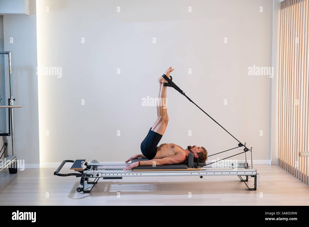 A man doing Pilates on a reformer Stock Photo - Alamy