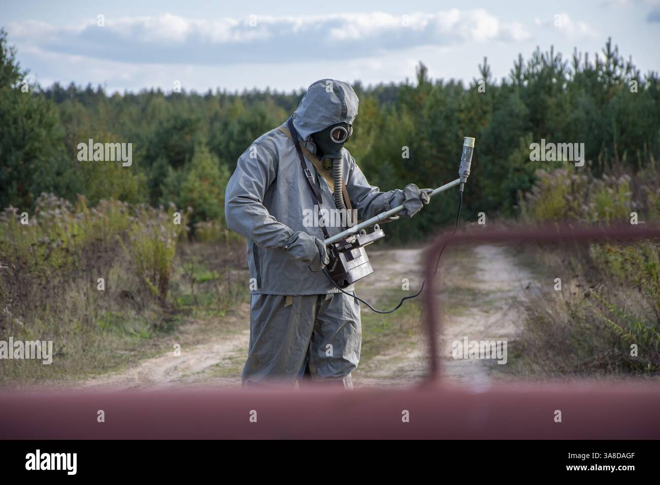 A military man in a protective suit and gas mask conducts radiation ...
