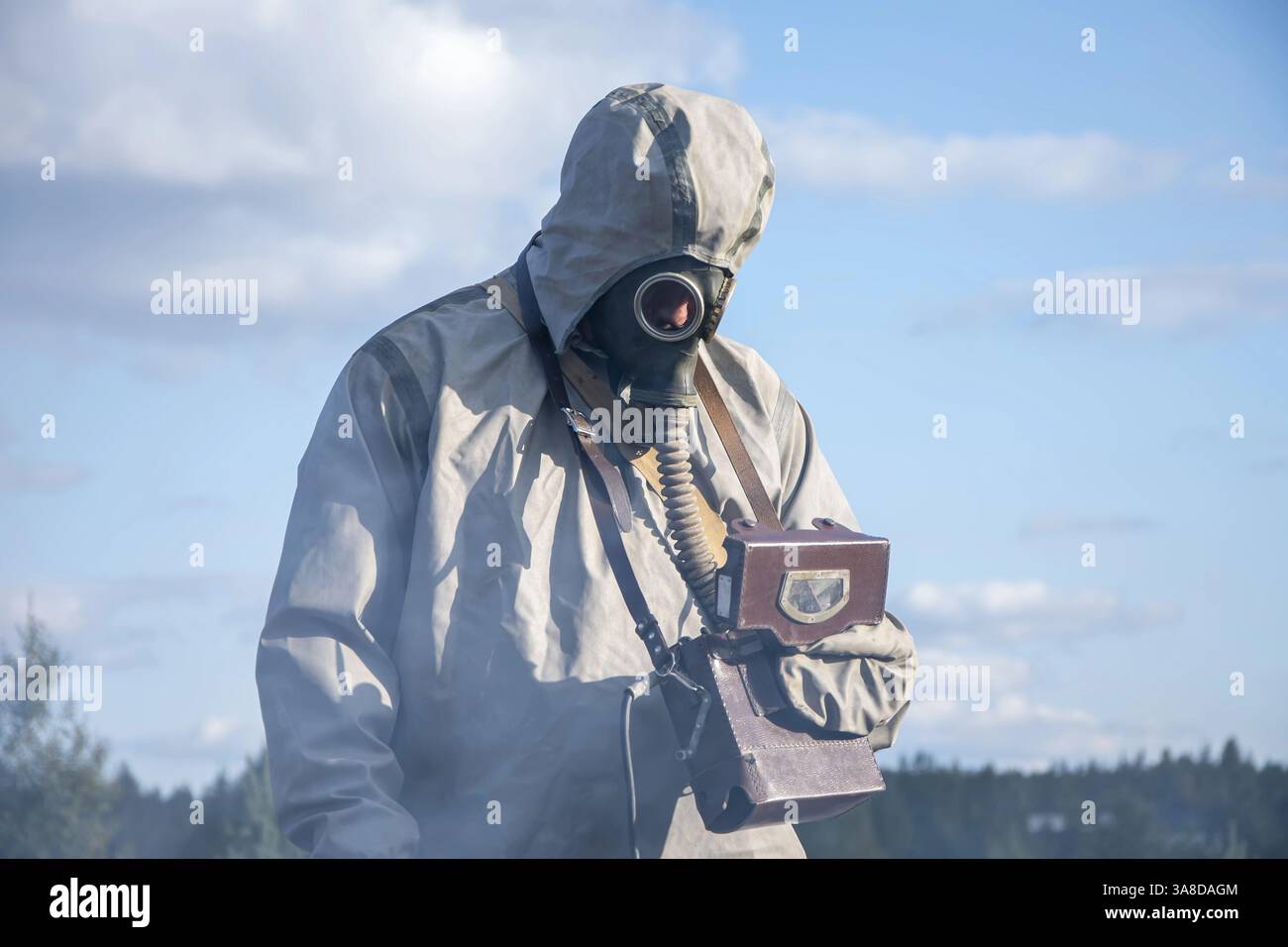 A military man in a protective suit measures radiation background in an ...