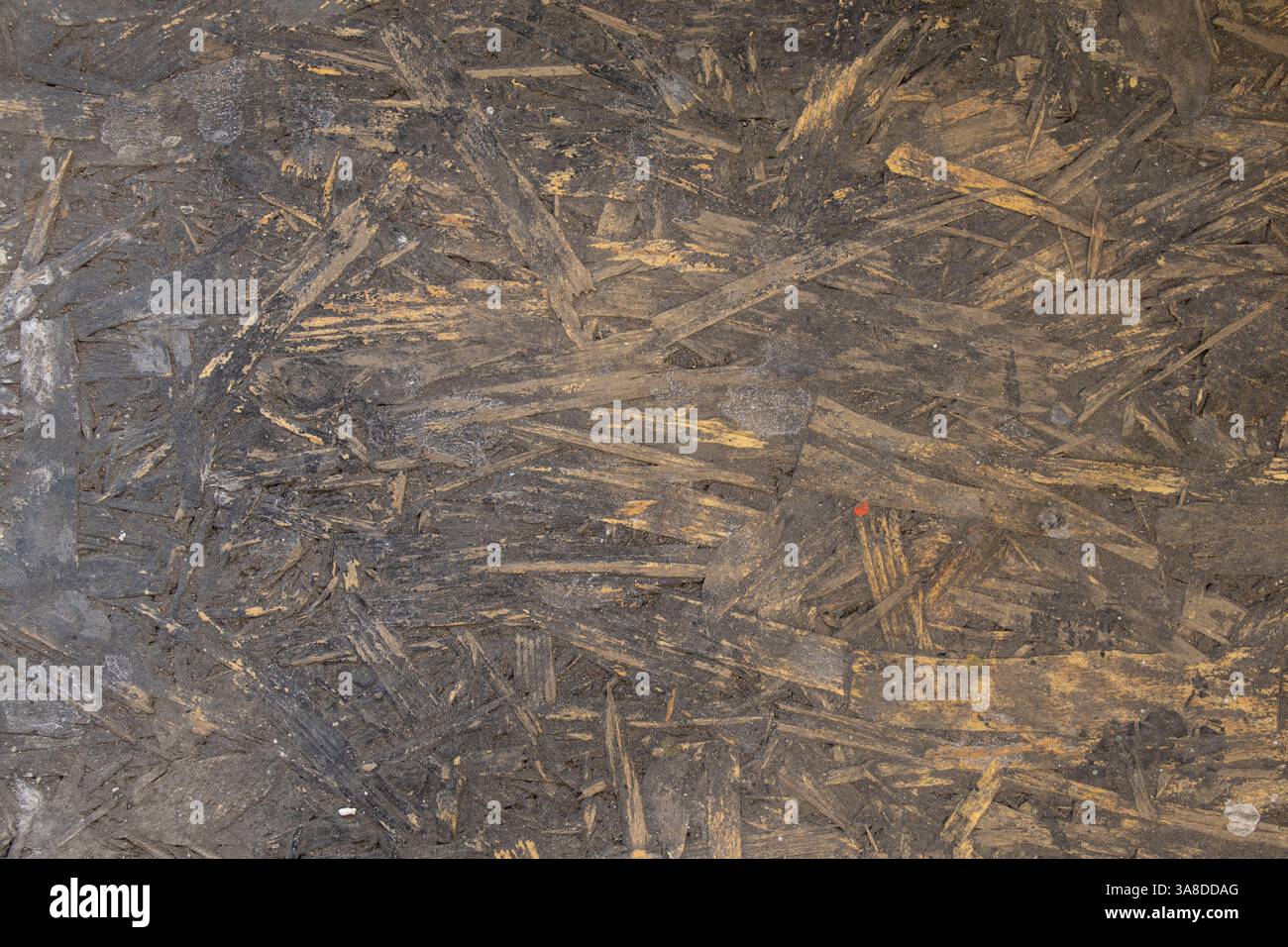 Pressed yellow dirty chipboard in black paint and earth on the floor ...