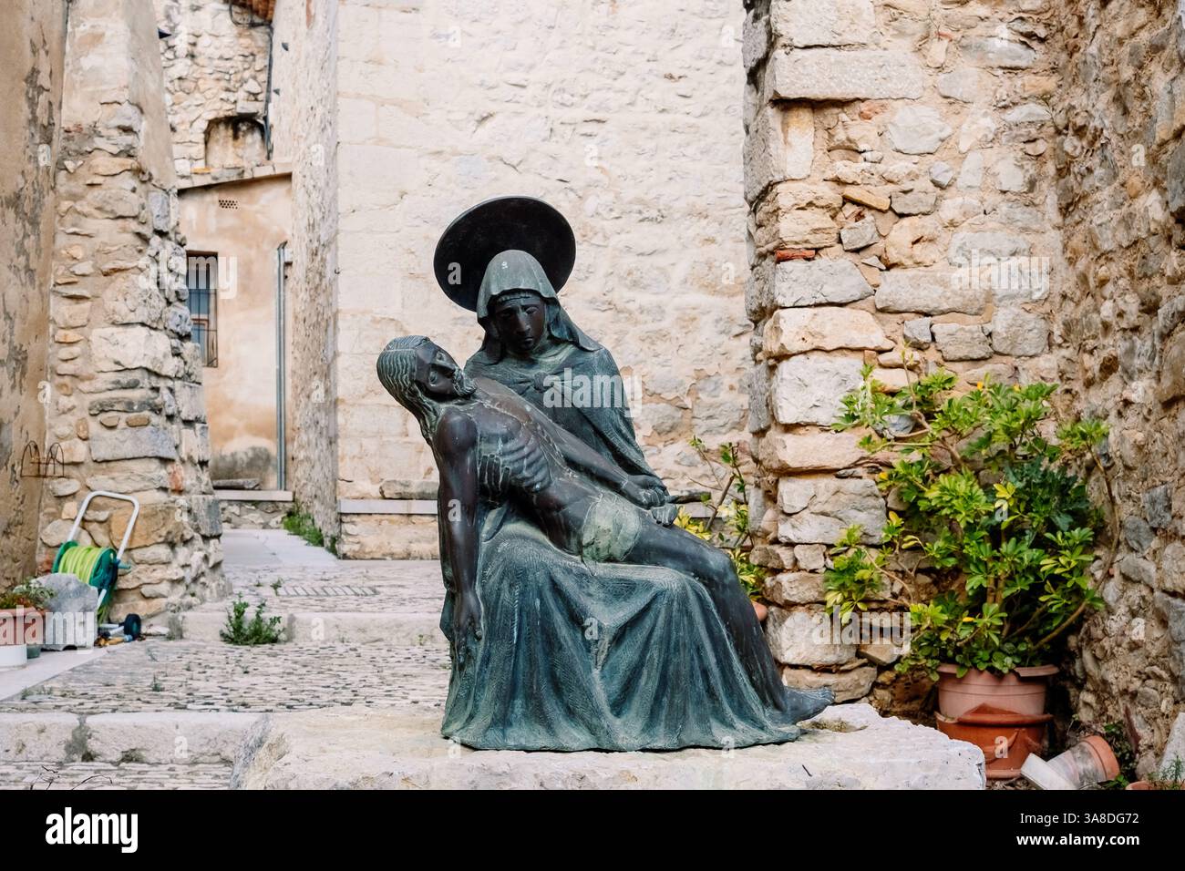 A detailed bronze sculpture depicts the Virgin Mary holding the ...