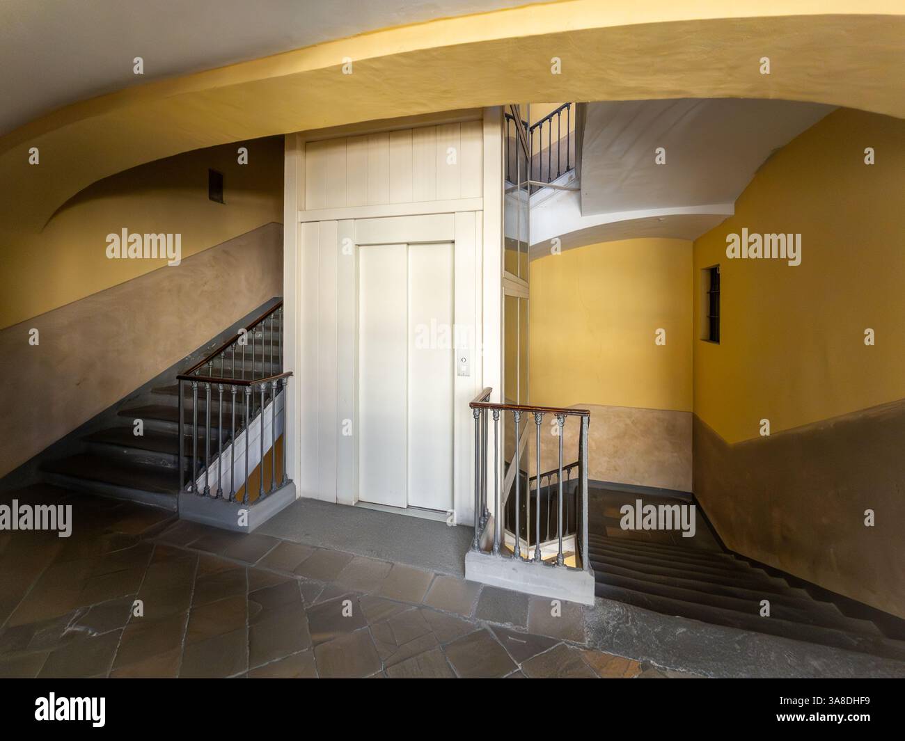 Landing with stone floor with elevator door built inside the stairwell ...