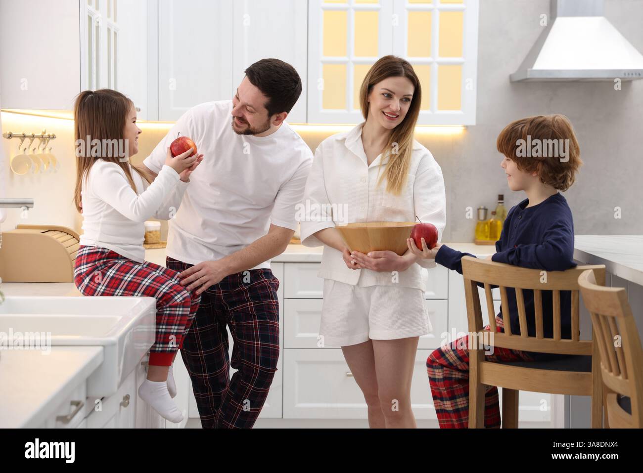 Happy family wearing stylish pajamas spending time together in kitchen ...