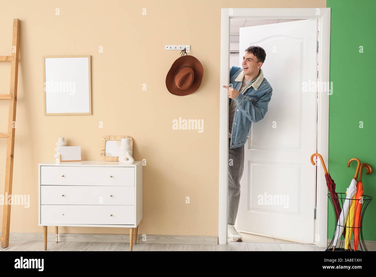 Young man pointing at something through open door in hall Stock Photo ...