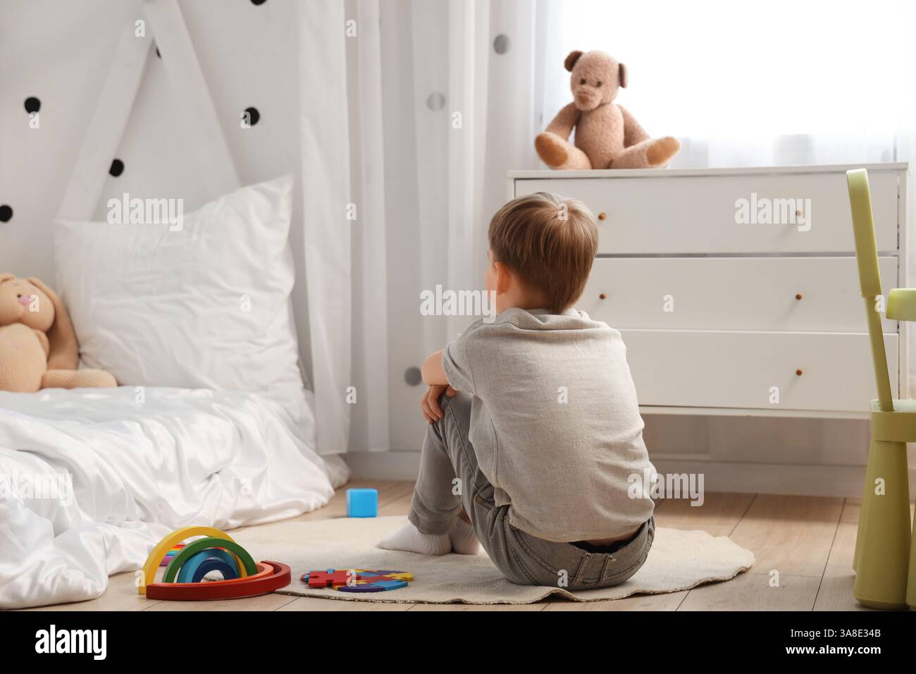 Sad little boy with autistic disorder sitting on floor in bedroom, back ...
