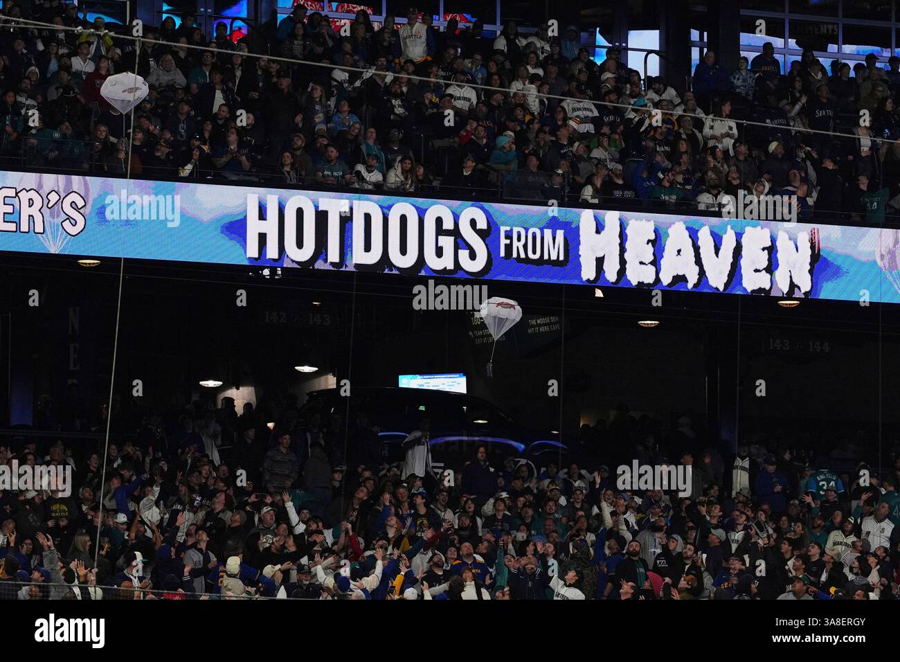Fans vie for hot dogs attached to small parachutes during the Seattle ...