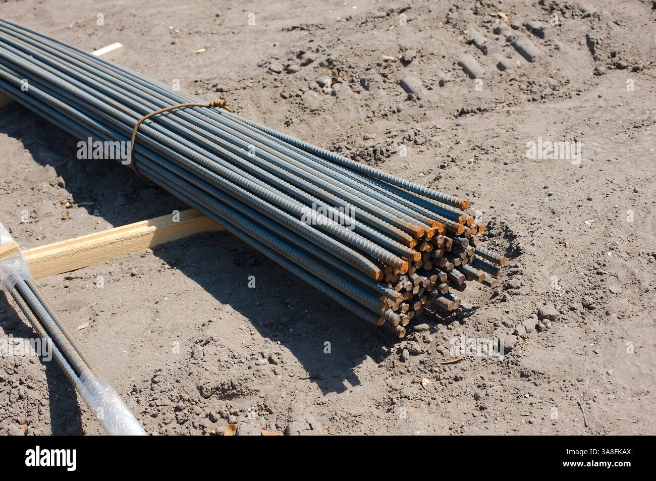 Close up bundle of steel reinforcing rebar, resting on dirt with wooden ...