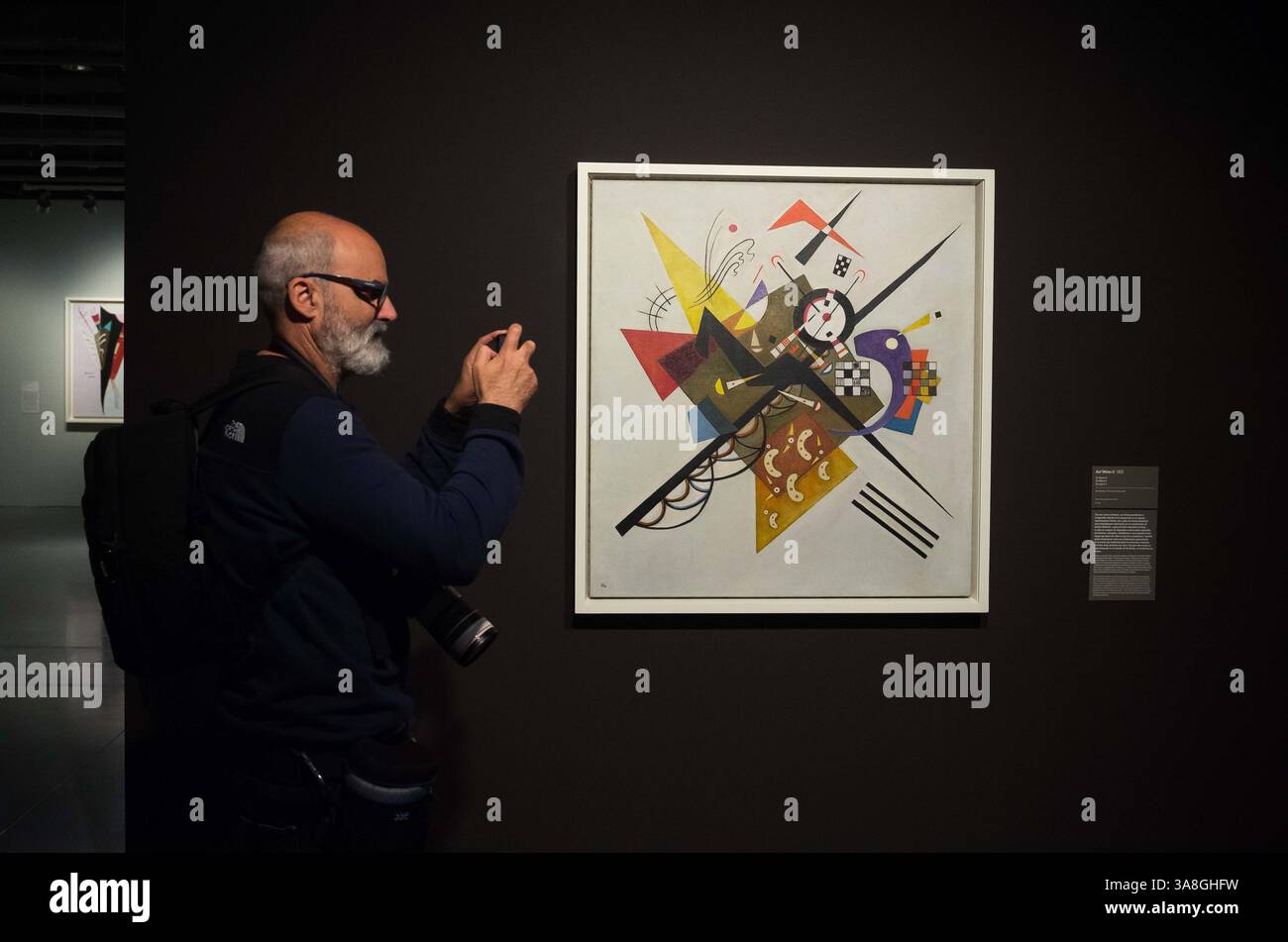 A man takes a photo of the painting title: "Vassily Kandinsky, Auf ...