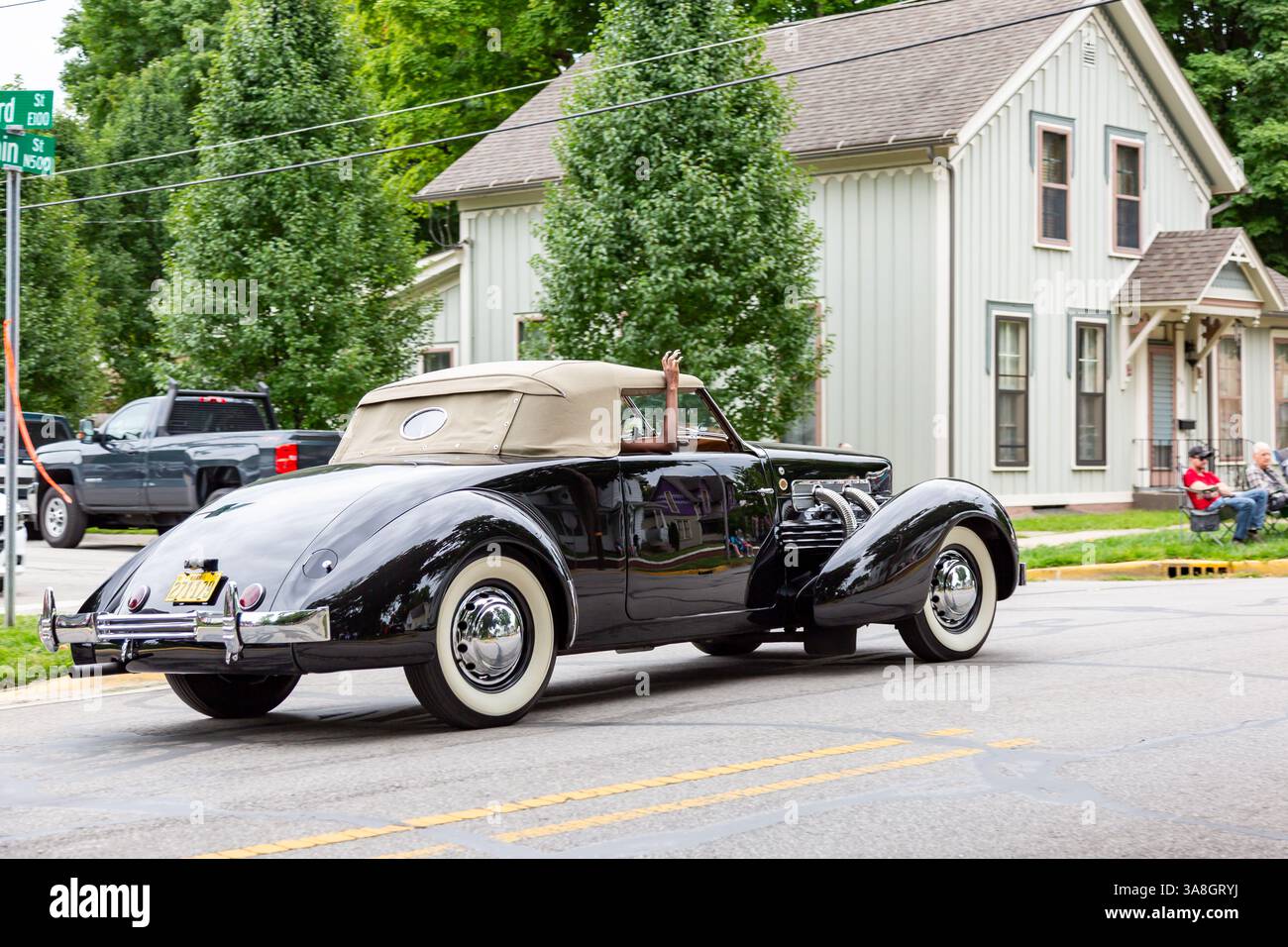 A black 1937 Cord 812 Sportsman passes through a neighborhood during ...