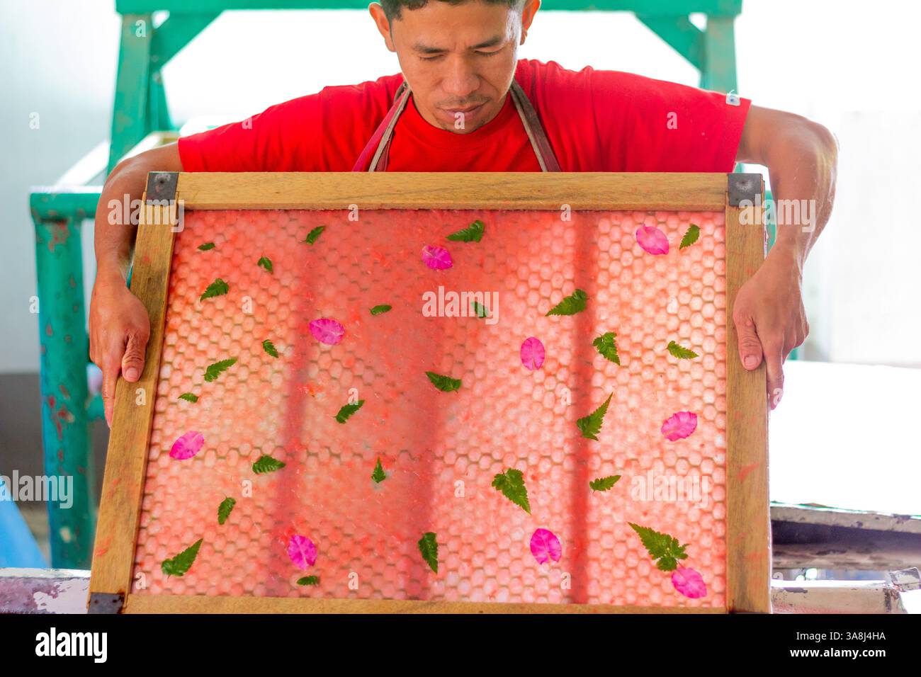 A Filipino man makes handmade paper inside a handicraft shop in Kalibo ...