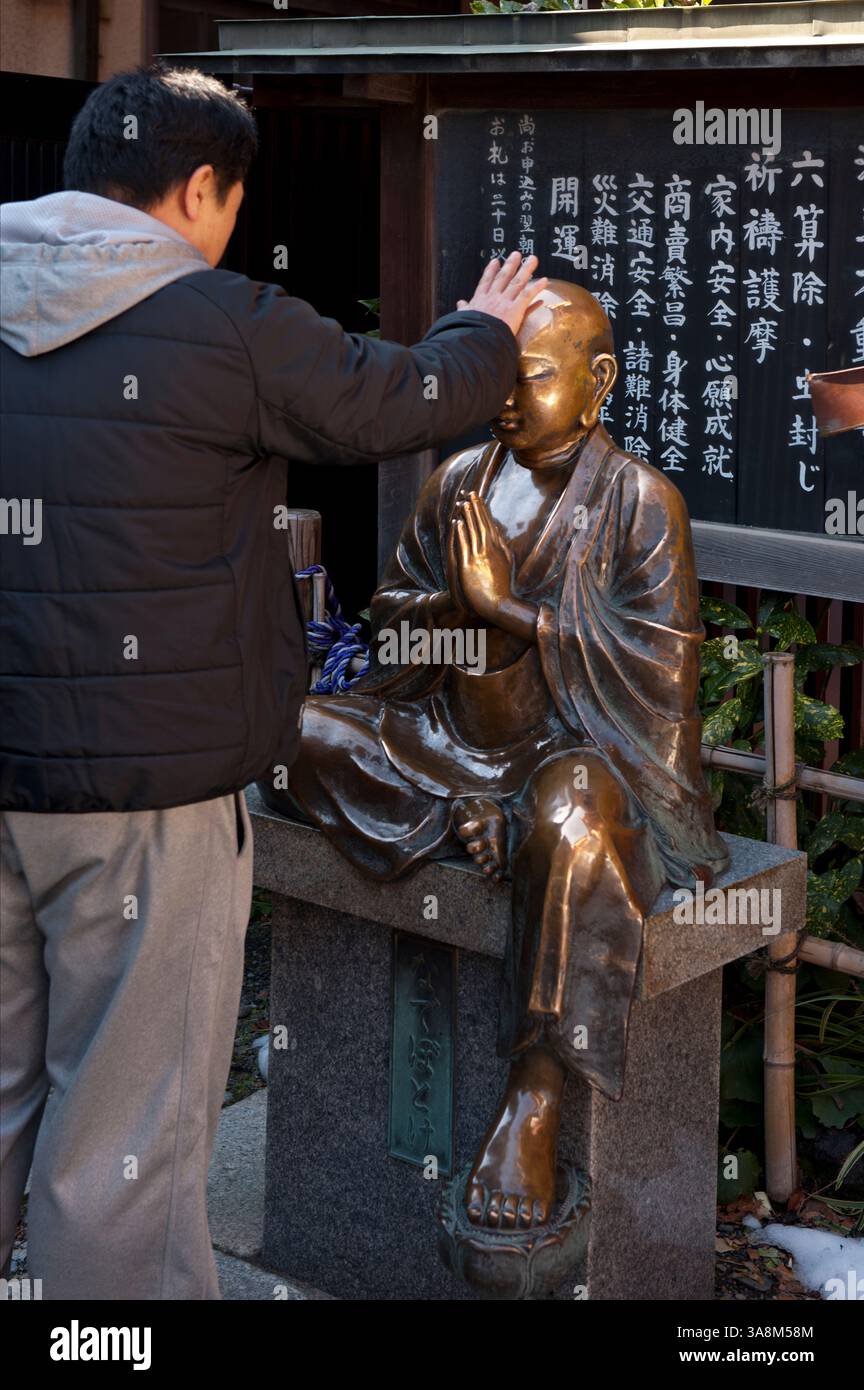 Worshipers rub and touch a sacred bronze healing Buddha statue at ...