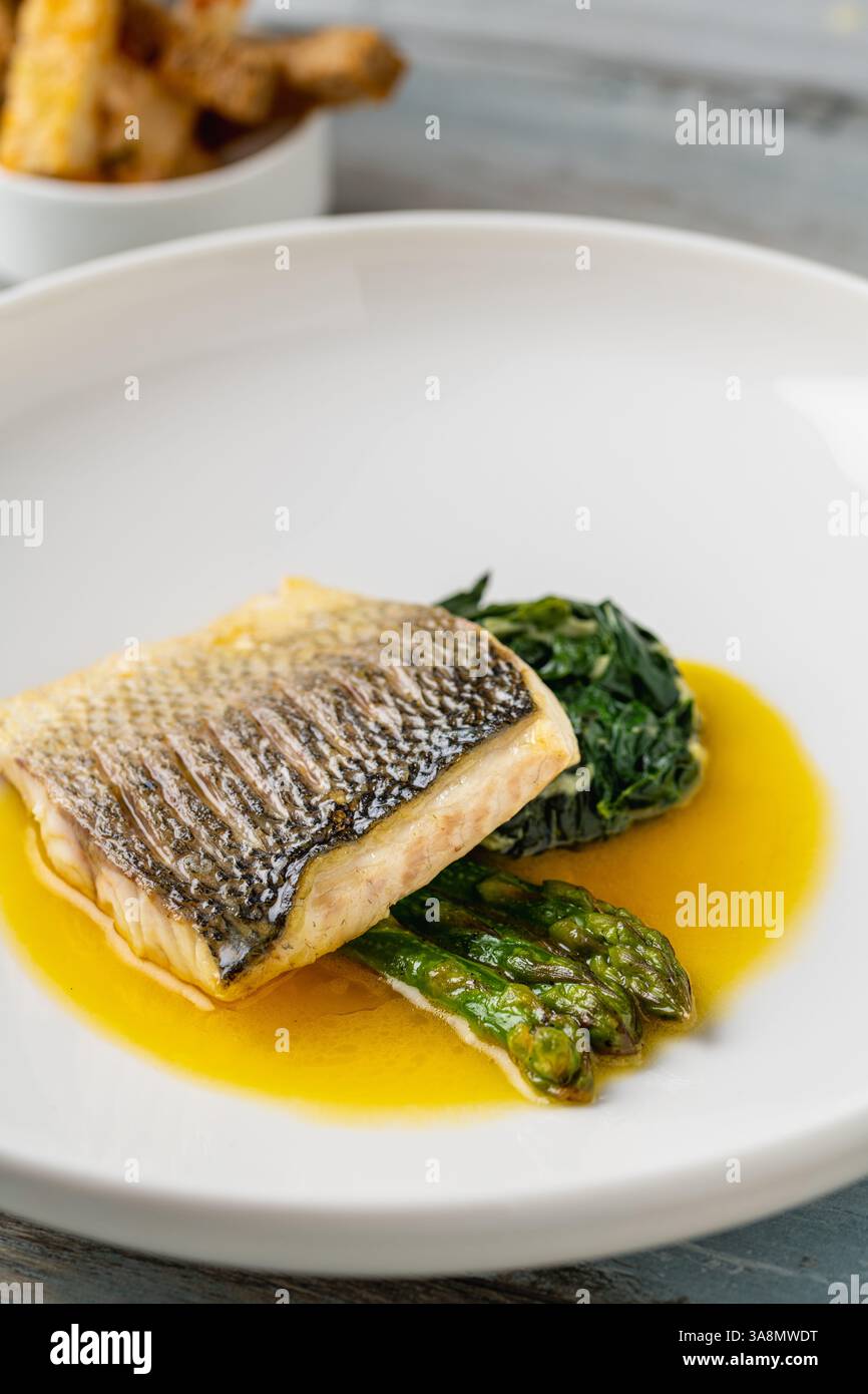 Grilled sea bass fillet served with garnishes in a fine dining ...