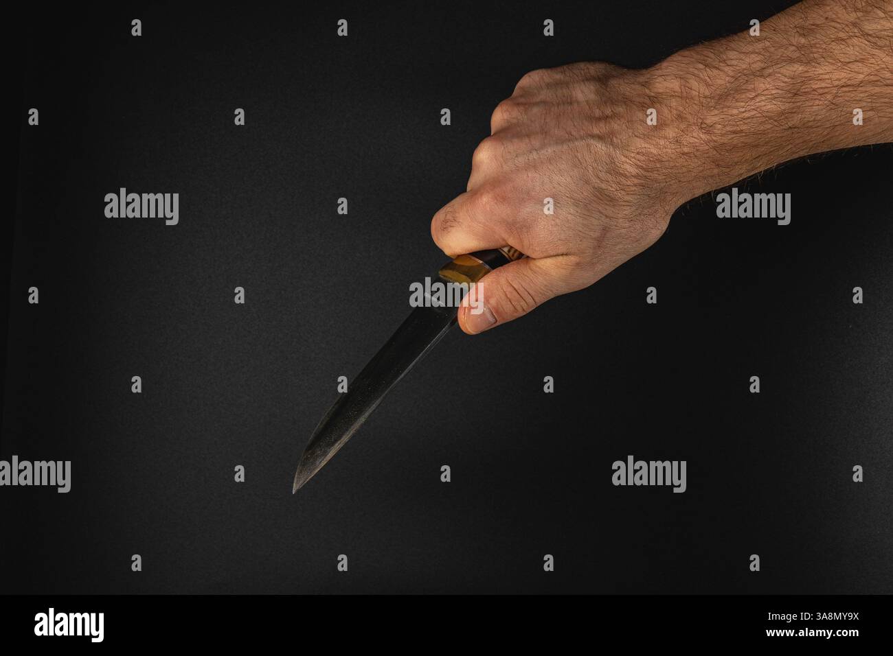 A hand firmly grips a knife, showcasing the blade's sharp edge. The ...