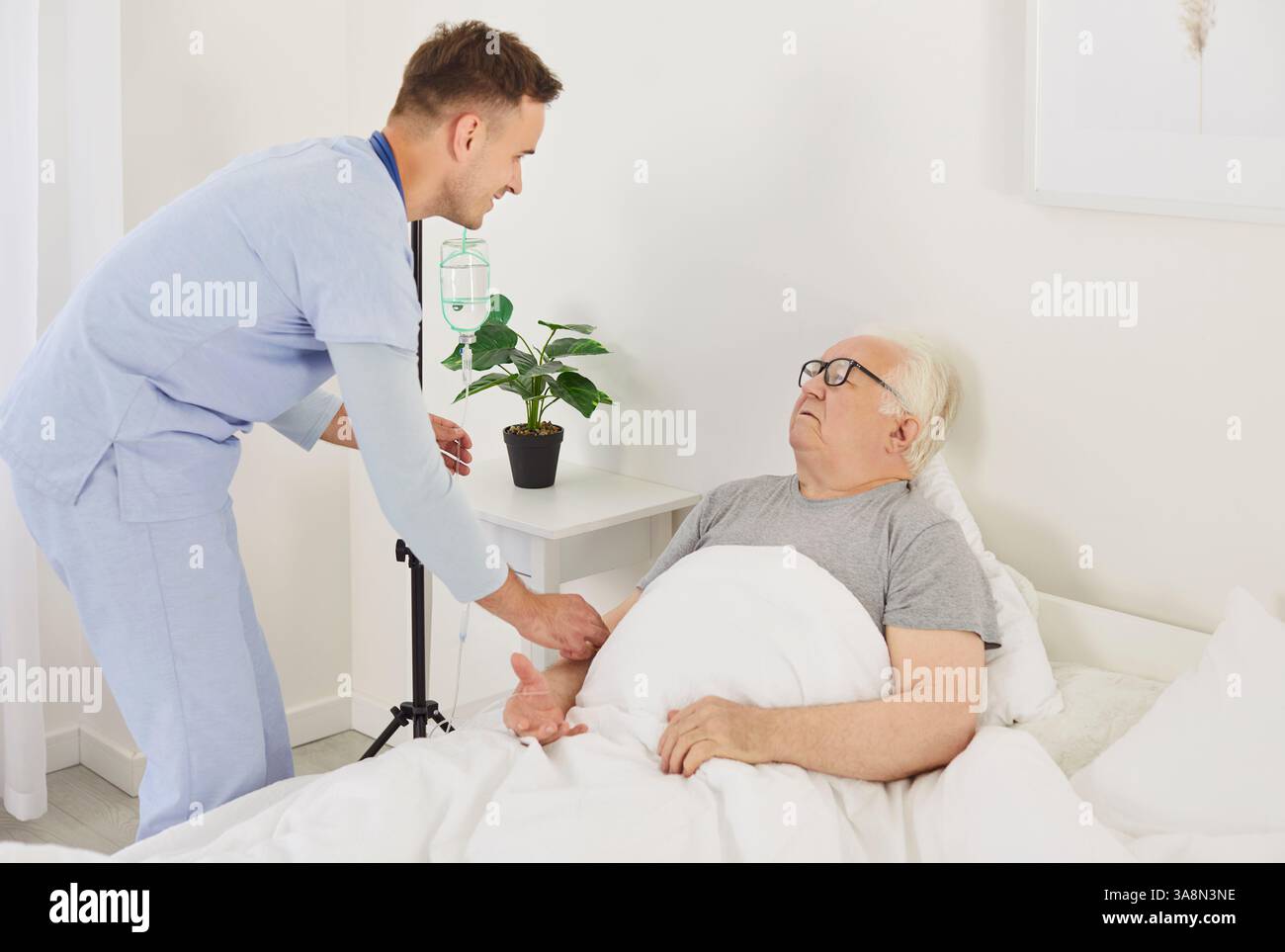 Young friendly nurse man helping a senior patient receiving iv drip ...