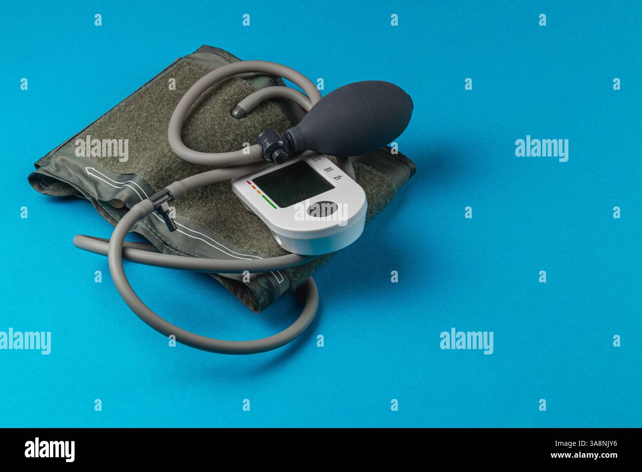 Automatic blood pressure monitor rests next to cuff and bulb pump on a ...