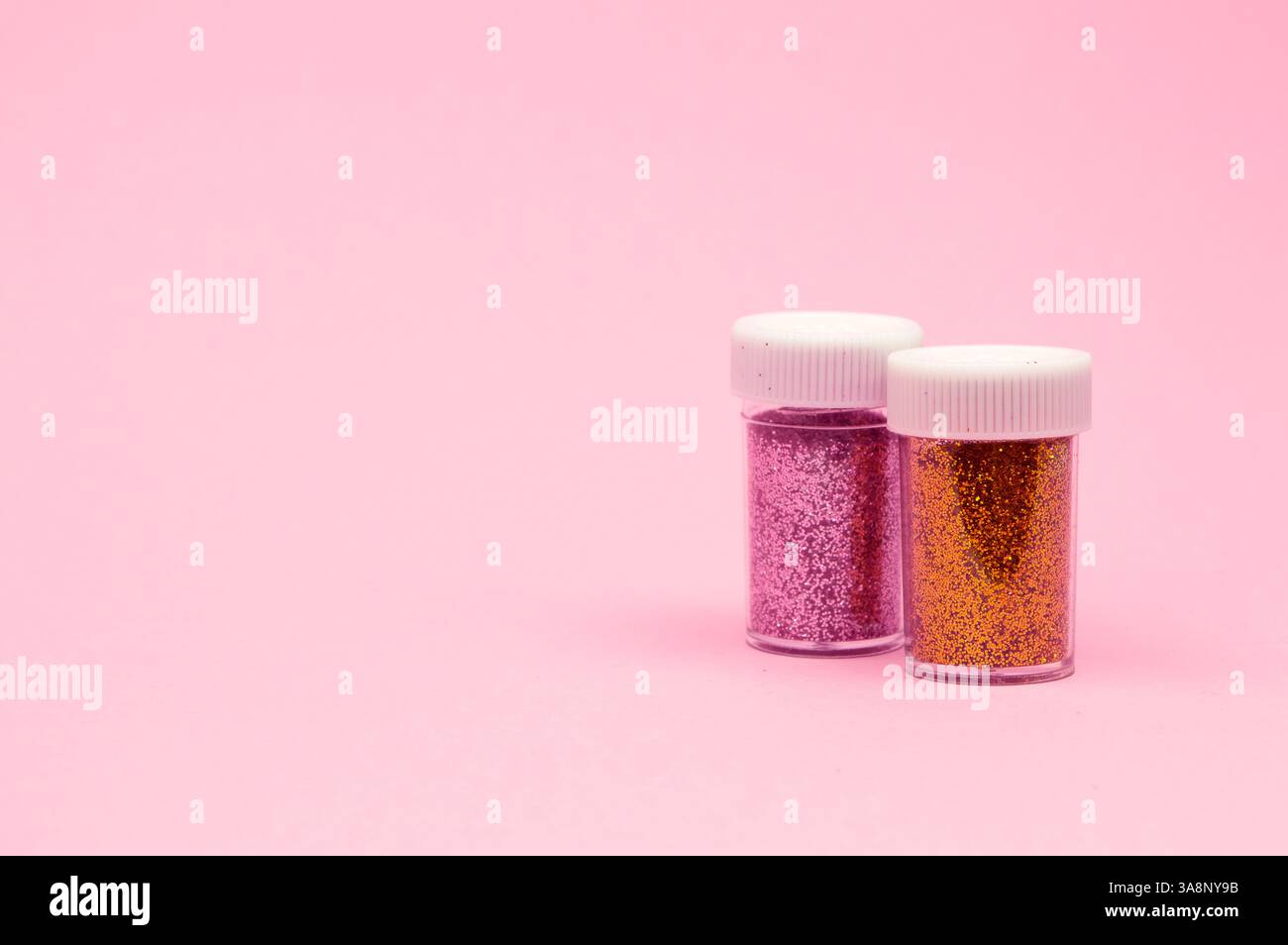 Tiny, sparkling sequins in vivid colors fill small containers, set ...