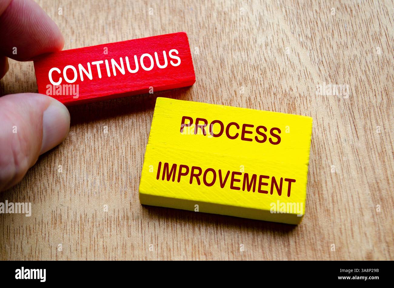 Hand holding Continuous Process Improvement text on colored wooden ...