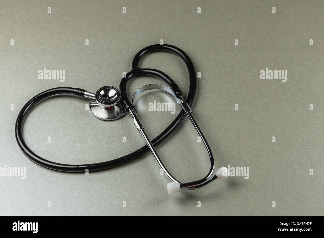 A stethoscope lies on a flat gray surface, showcasing its glossy finish ...