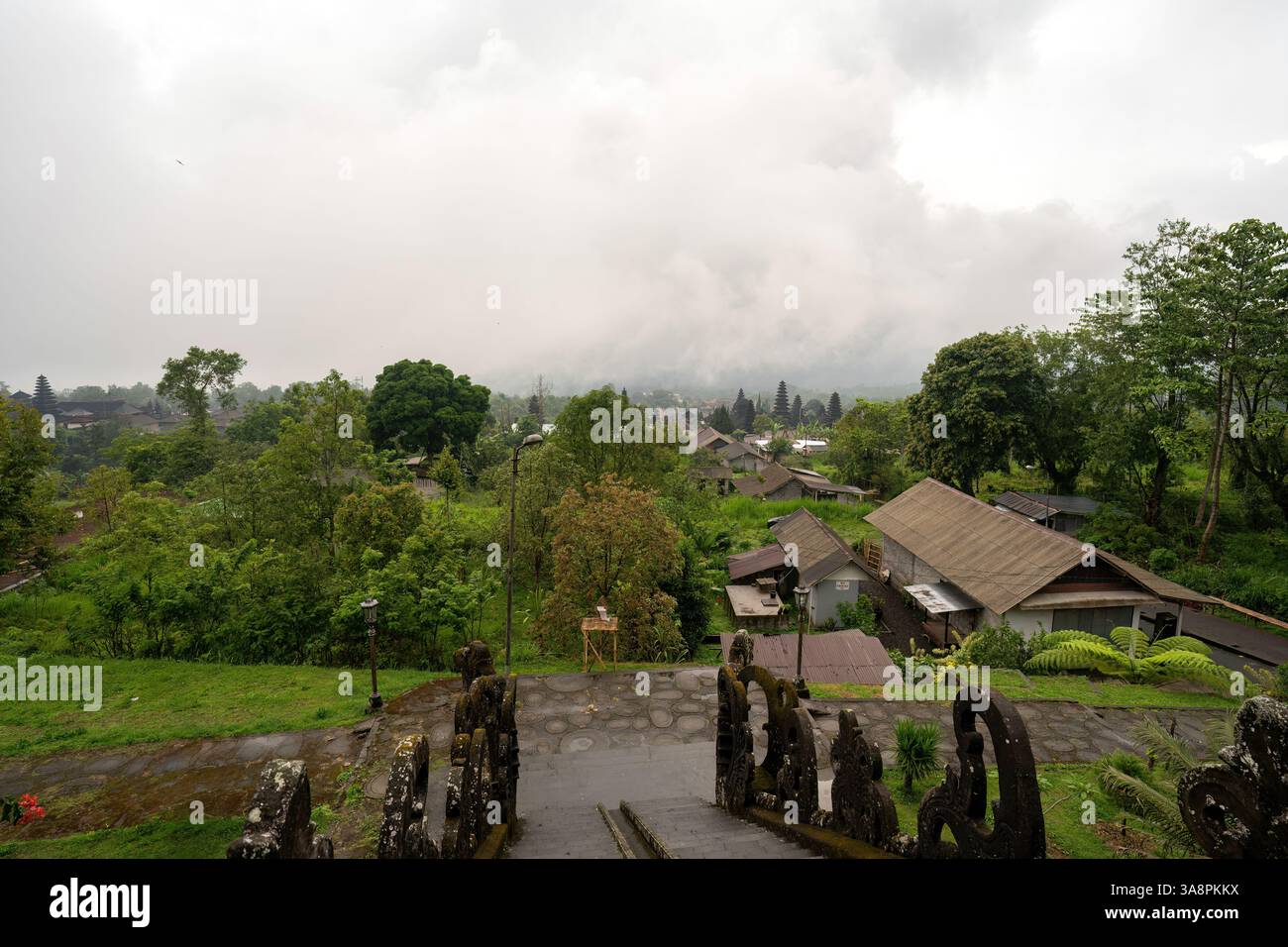 A misty Balinese village nestled among lush greenery, viewed from an ...