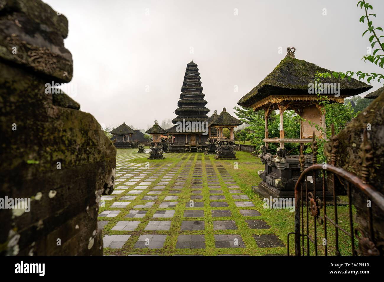 Ancient Balinese temple courtyard with towering multi-tiered meru ...