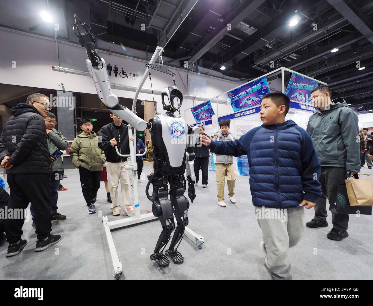 BEIJING, CHINA - MARCH 29, 2025 - A child interacts with a humanoid ...