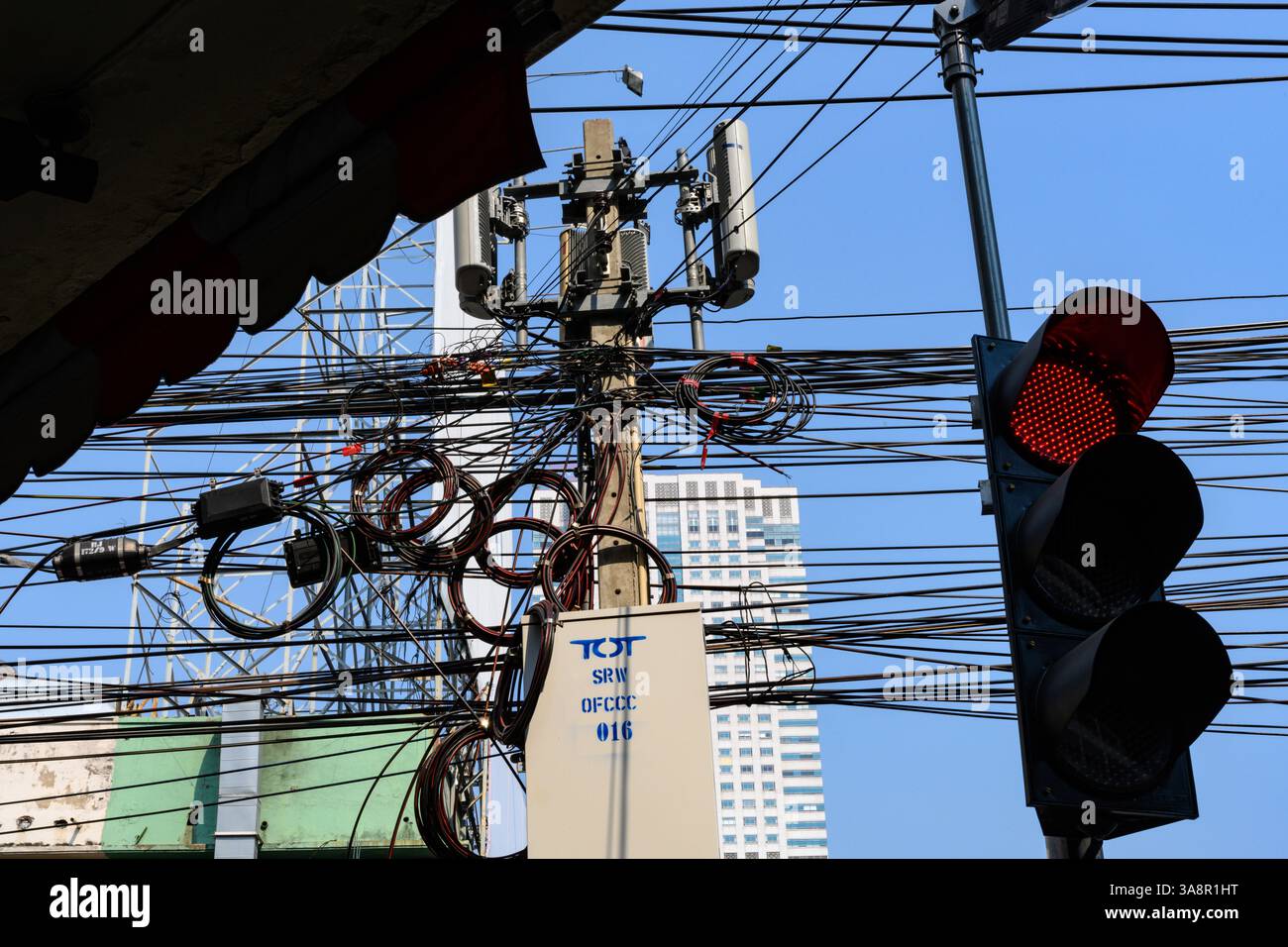 A red traffic light with a tangled mess of cables and wires with mobile ...