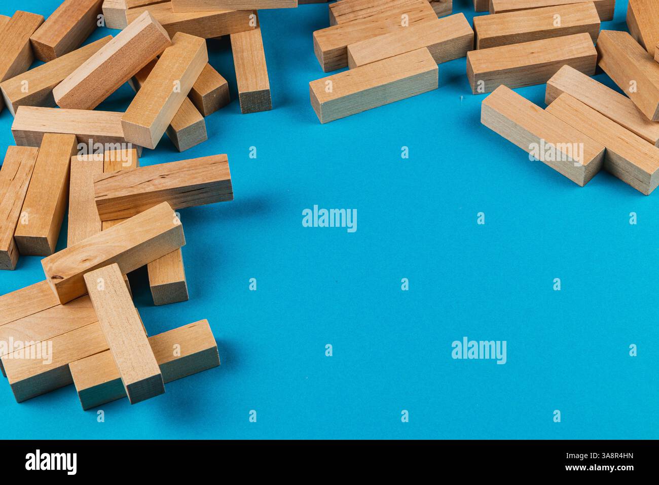 A collection of wooden blocks is scattered across a bright blue surface ...