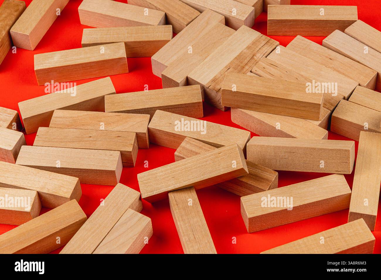 A collection of wooden blocks is scattered on a bright red surface. The ...