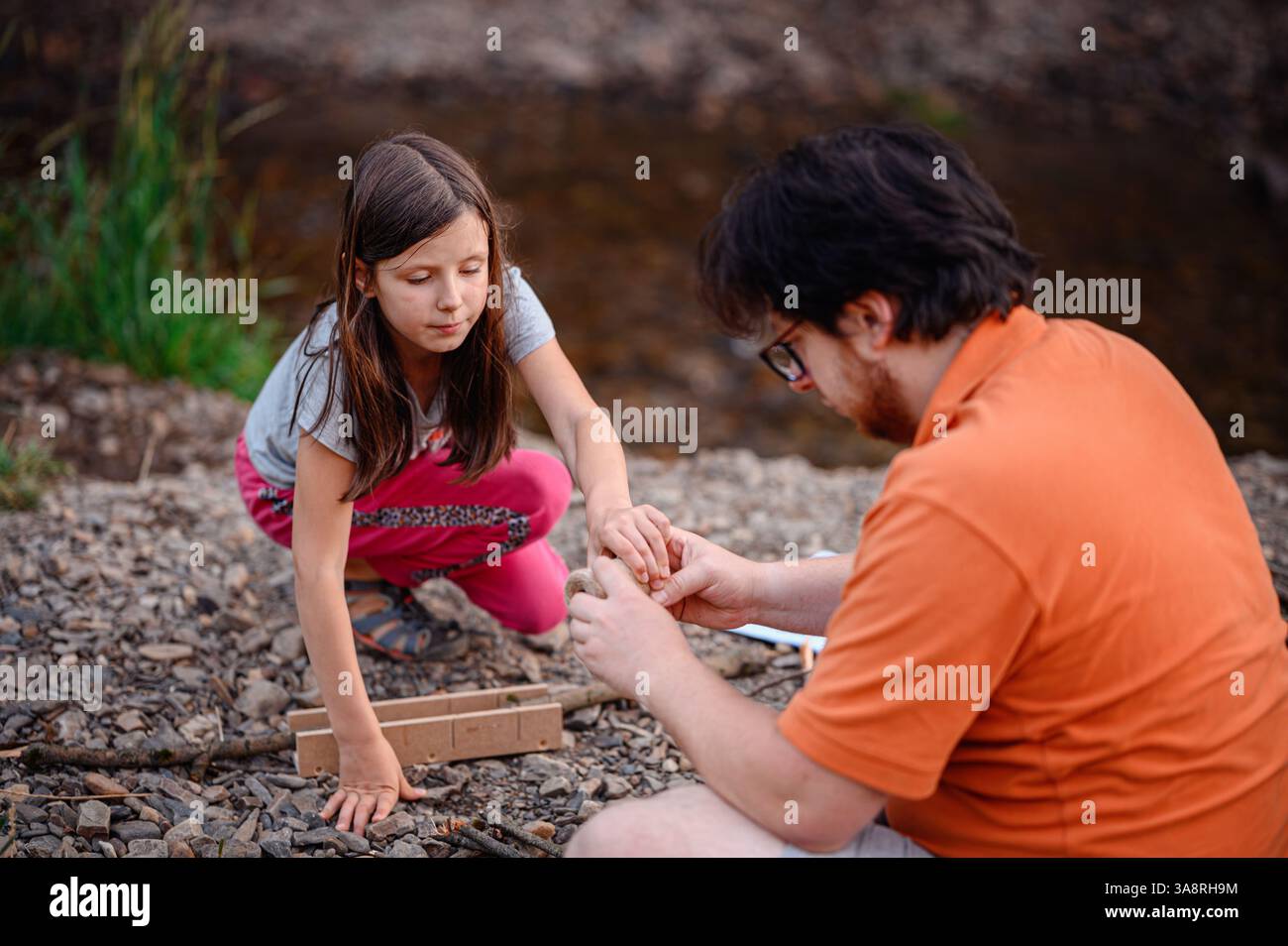 A father and daughter engage in a hands-on outdoor activity, learning ...
