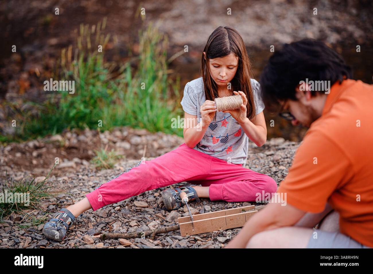 A father and daughter engage in a hands-on outdoor activity, learning ...