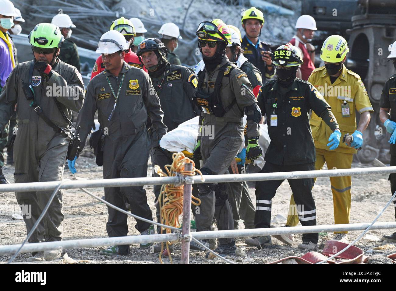 Thai rescue workers carry a body from a high-rise building under ...