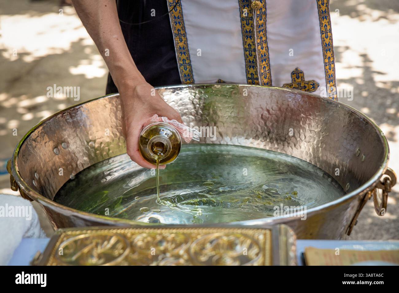 The priest pouring oil over the holy font during a greek orthodox baptism Stock Photo - Alamy