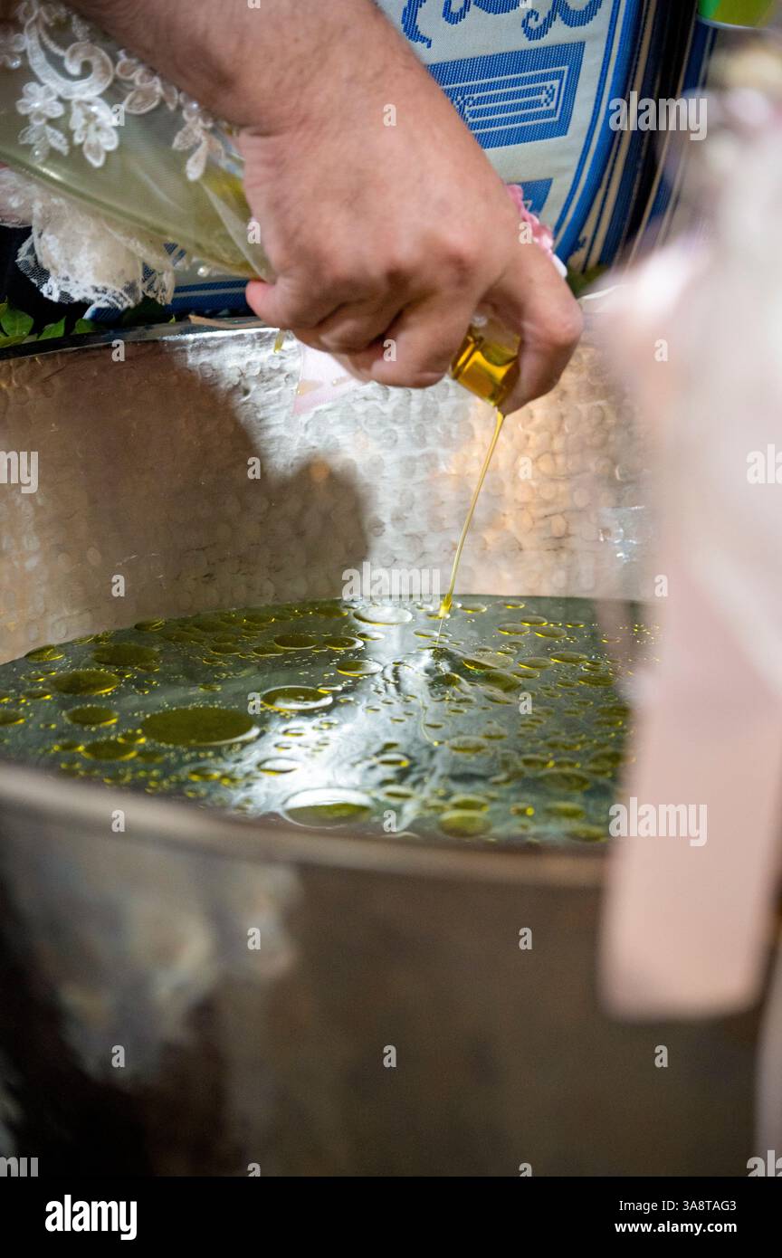 The priest pours olive oil in the font where the baby will be immersed ...