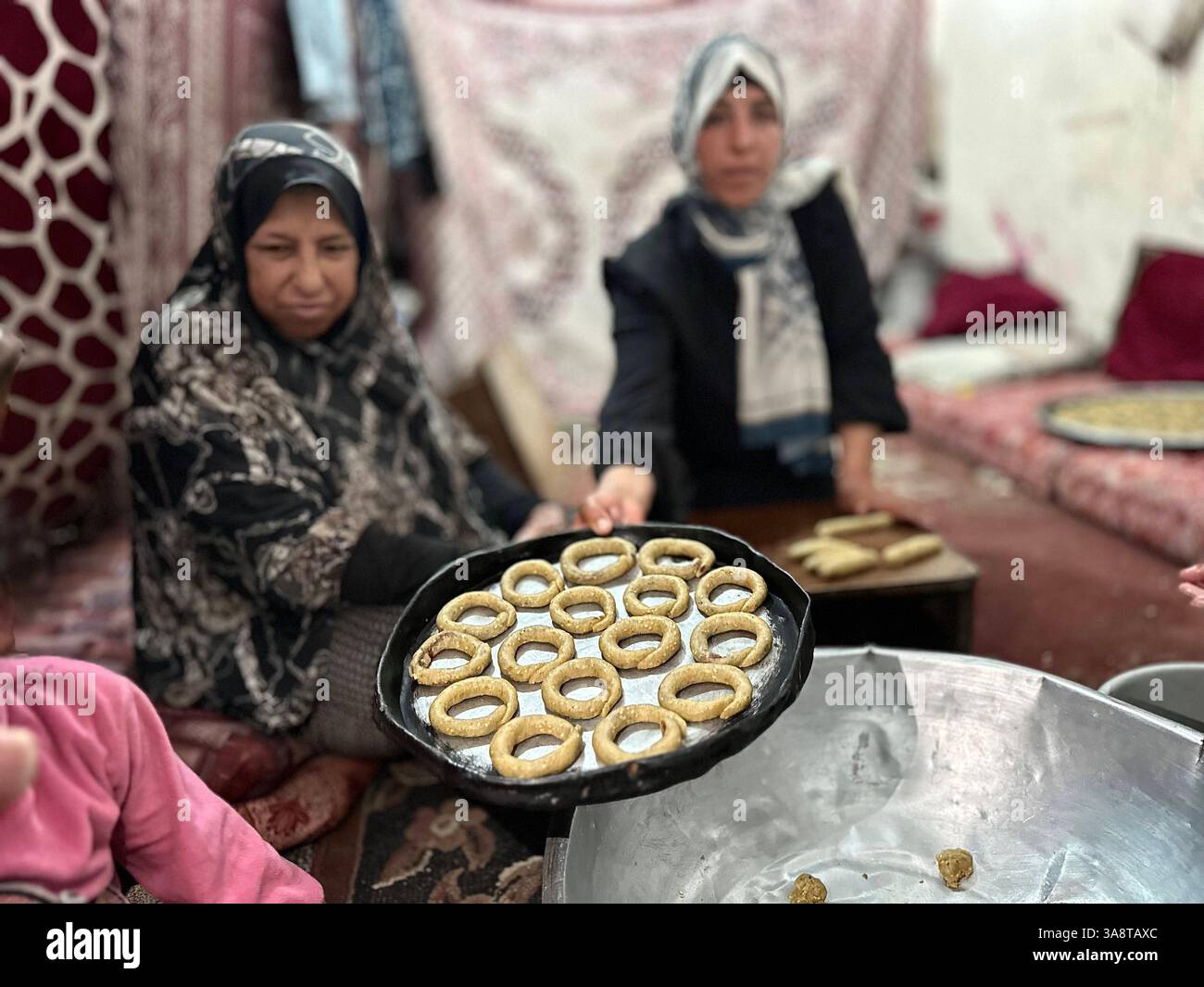 A Palestinian family prepares traditional cookies in preparation for ...